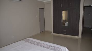 Quarto com cama, guarda-roupa e ar condicionado.
