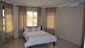 Quarto com cama, cortinas e ar-condicionado.