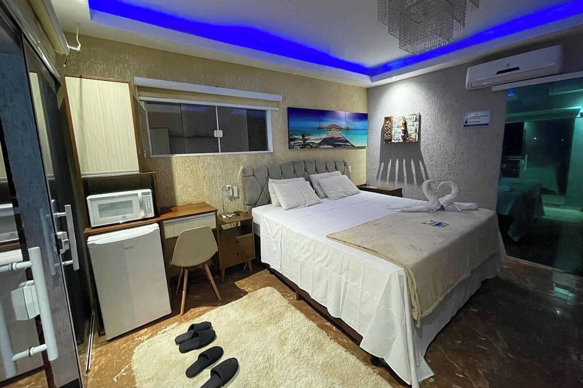 Quarto de hotel moderno com cama, escrivaninha e área de estar.
