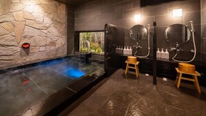 Uma área de spa com hidromassagem, duas saunas e uma parede de pedra.
