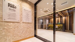 Um hall de hotel moderno com painéis de parede de madeira e entrada de vidro.
