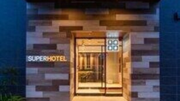 Entrada de hotel com design moderno, exibindo uma placa com a inscrição 'SUPERHOTEL'.