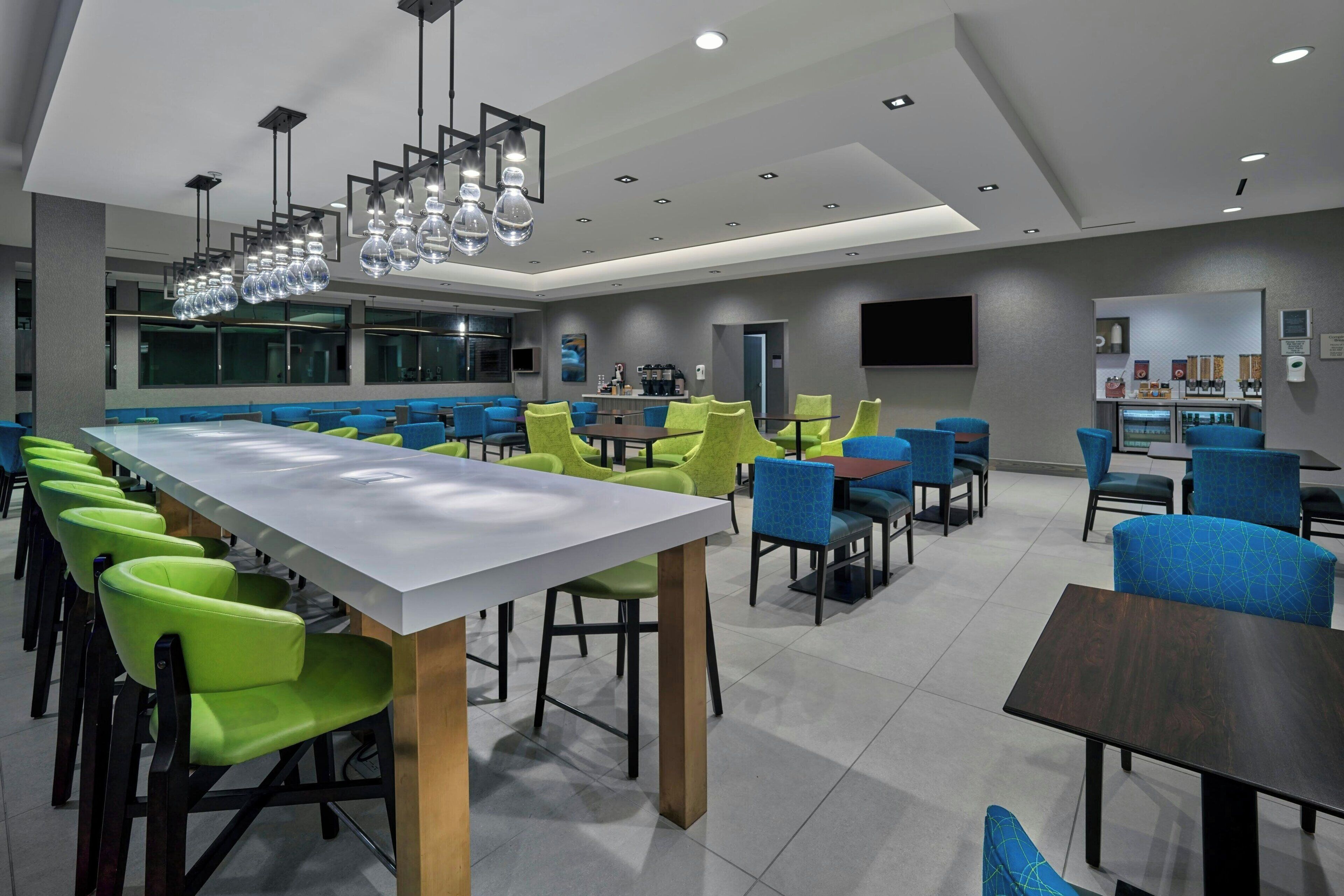 Uma sala de jantar moderna com uma mesa grande para todos, diversas opções de assento e um bar.