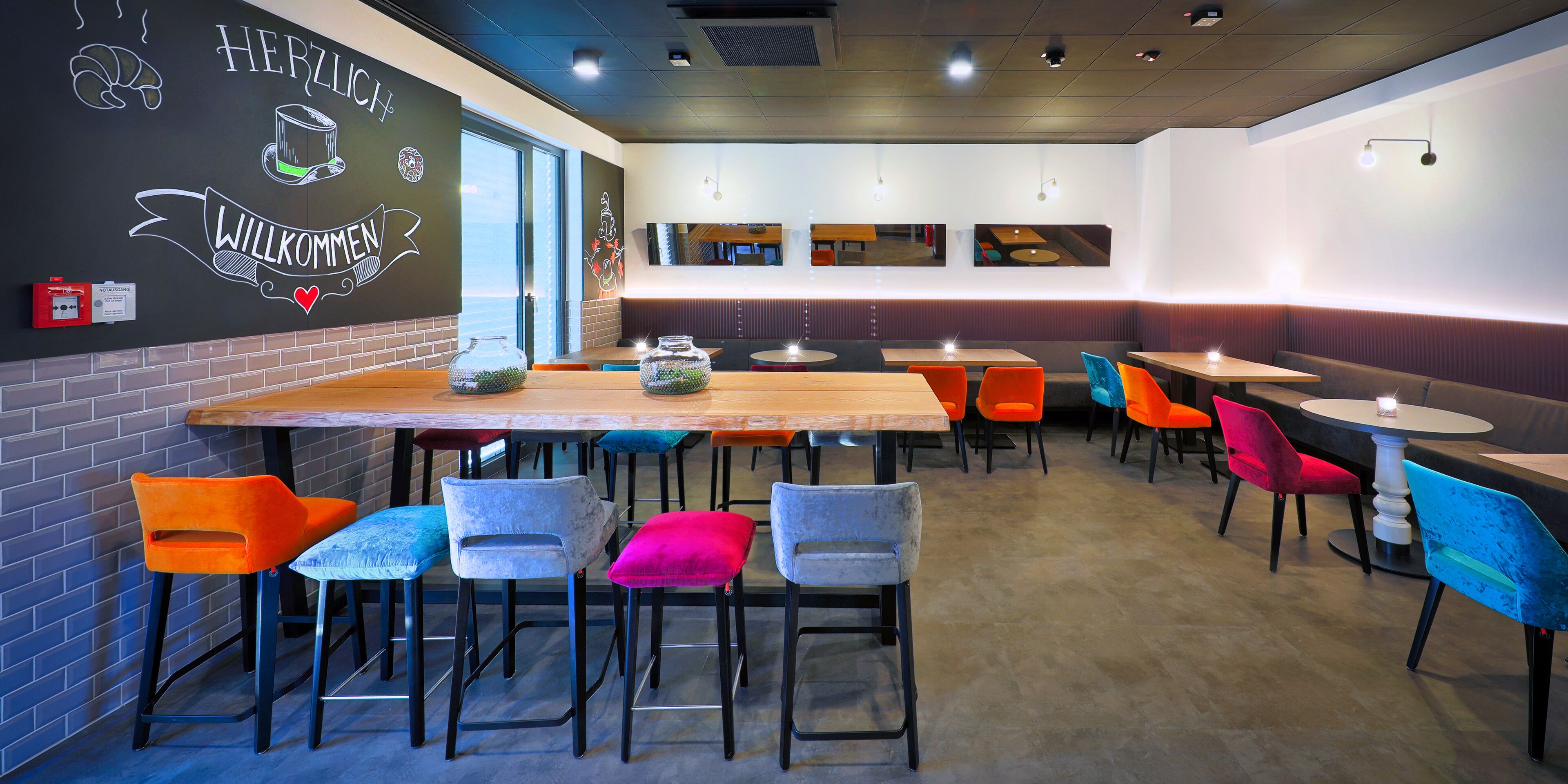 Um restaurante com parede de tijolos, cadeiras coloridas e mesas.