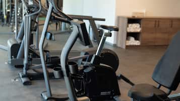 Uma academia com diversos equipamentos de exercícios, incluindo esteiras e elípticos, dispostos em fileiras.