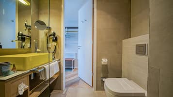 Casa de banho moderna com lavatório amarelo, espelho, sanita e zona de duche.
