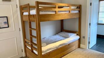 Uma cama beliche num quarto com porta e um aviso emoldurado na parede.