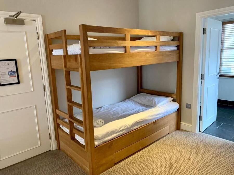 Uma cama beliche num quarto com porta e um aviso emoldurado na parede.