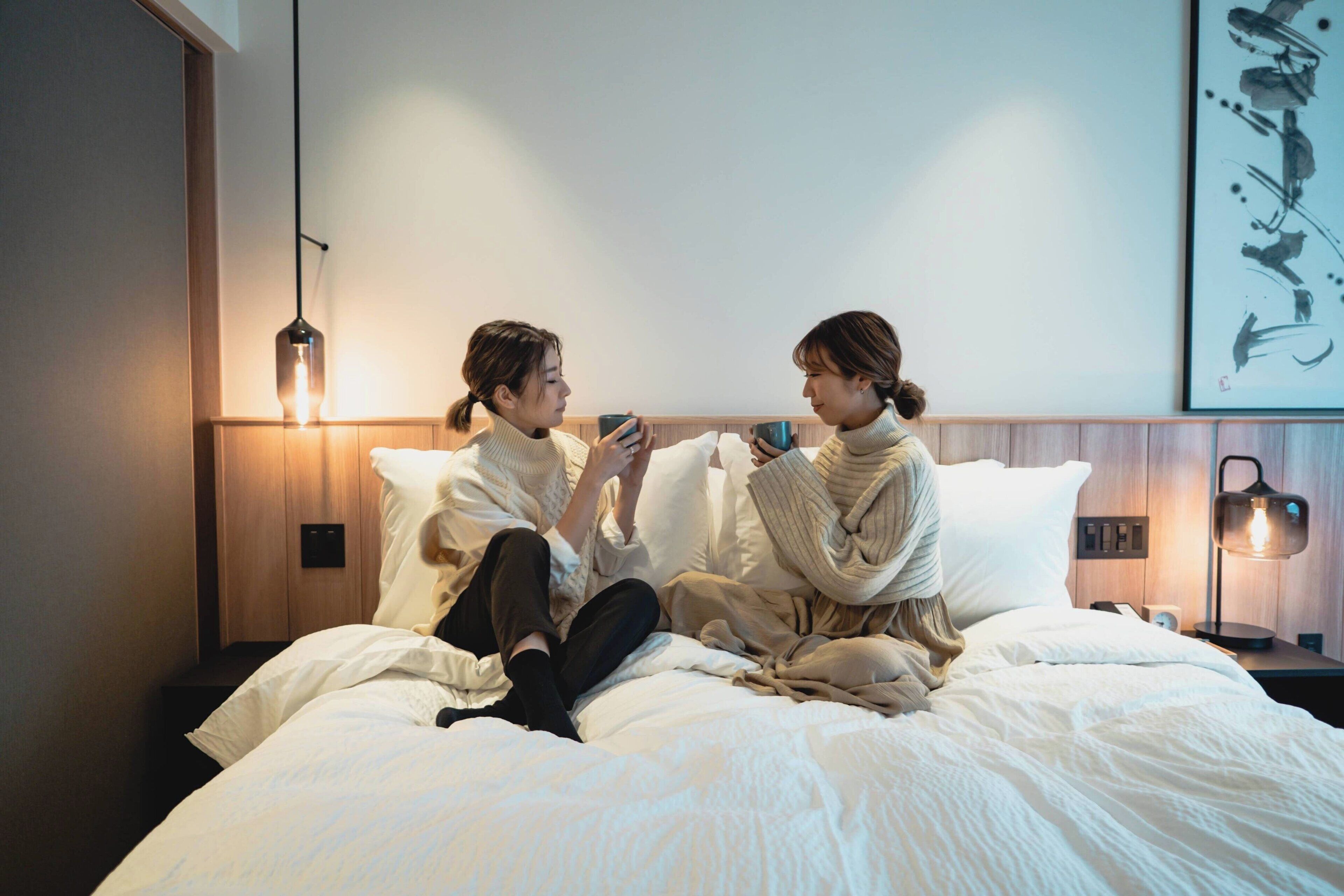 Quarto de hotel com cama, abajures e uma obra de arte na parede.