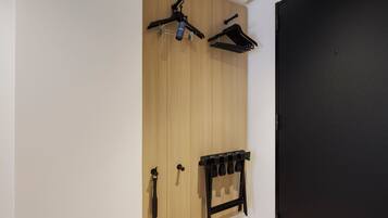 Um guarda-roupa com design de painel de madeira, porta preta e cabideiro preto.