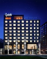 Um hotel de vários andares com um letreiro chamativo da Graduate, janelas amplas e fachada bem iluminada.