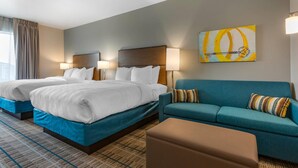 Quarto de hotel com duas camas, um sofá e um quadro na parede.