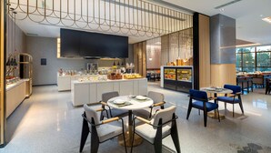 Um restaurante moderno com ilha central, áreas de estar e uma grande televisão de tela plana.