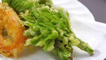 Prato com legumes fritos, incluindo um pedaço de couve-flor e um legume verde, possivelmente quiabo, sobre um guardanapo de papel branco.