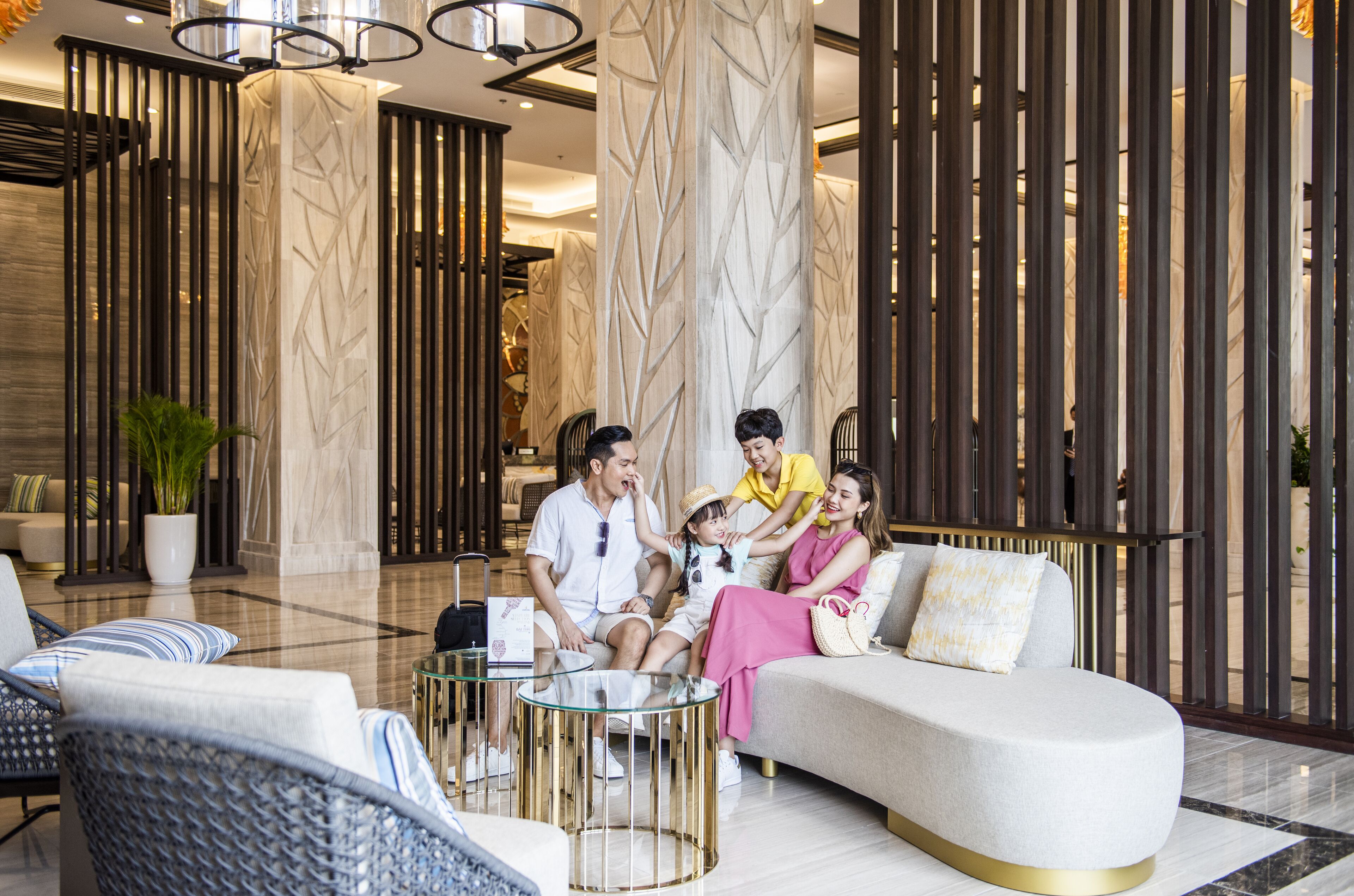 Um lobby moderno com área de estar, uma grande planta em vaso e um painel decorativo.