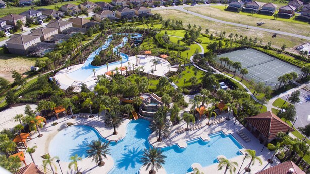 Vista aérea de um resort com várias piscinas, palmeiras e uma quadra de tênis.