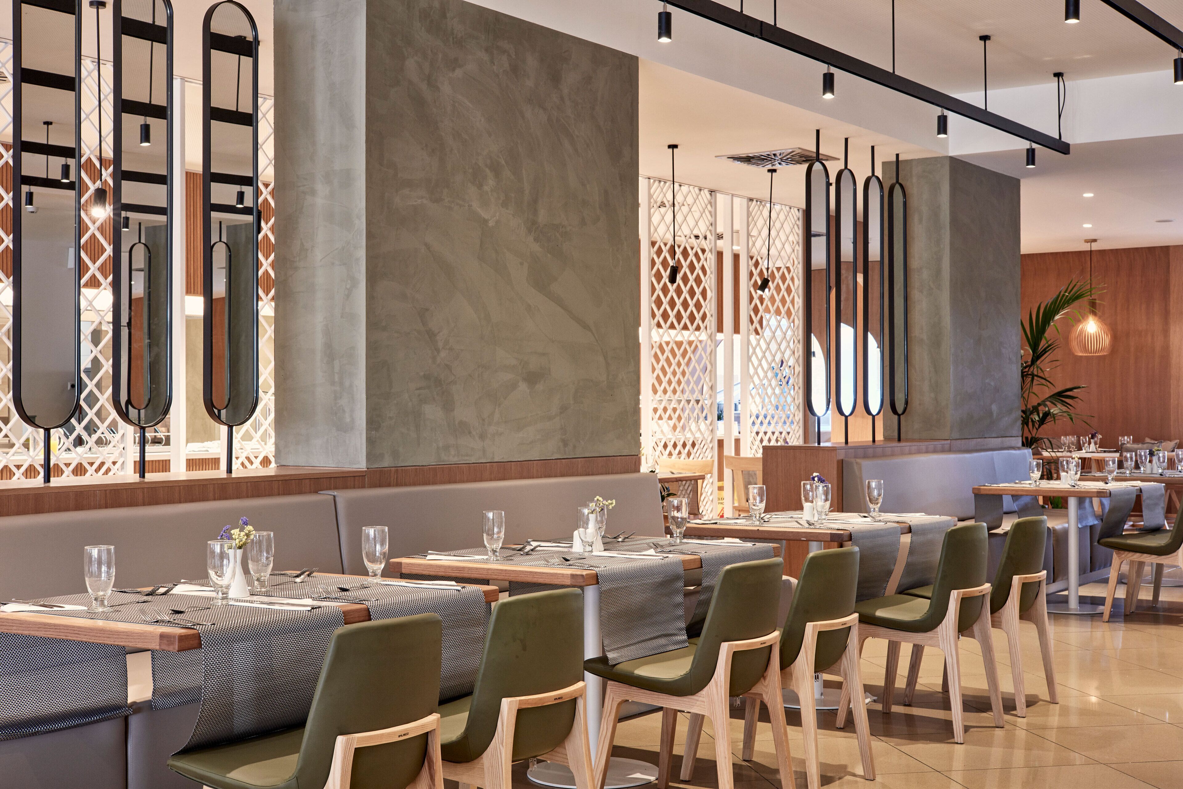 Um interior de restaurante moderno, com assentos em camarotes, mesas e uma parede decorativa.