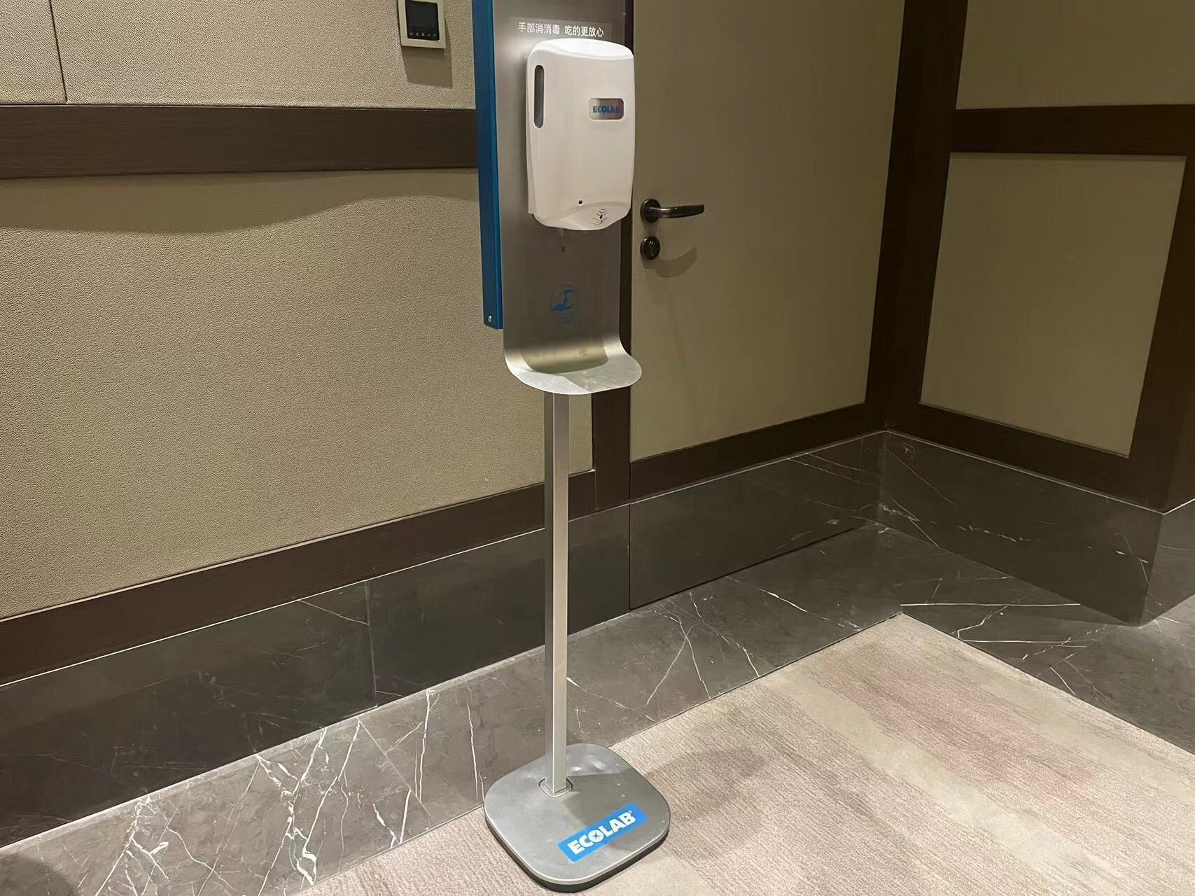Um dispensador de álcool em gel fixado na parede perto de uma porta.