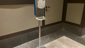 Um dispensador de álcool em gel fixado na parede perto de uma porta.