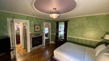 Quarto com cama, lareira e vista para um jardim através de uma janela.