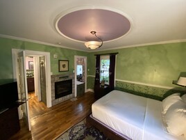 Quarto com cama, lareira e vista para um jardim através de uma janela.