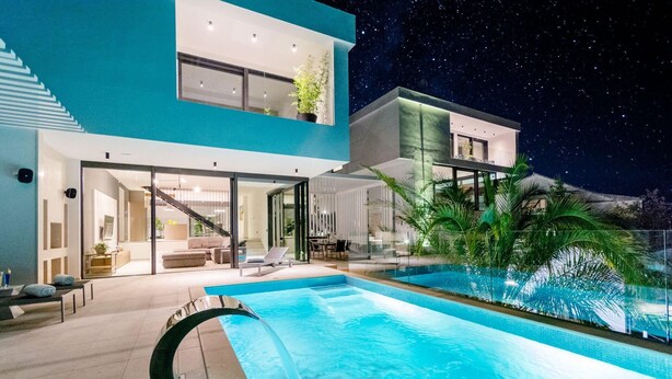 Uma casa moderna com piscina, janelas amplas e escadaria para o andar superior.