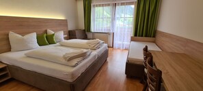 Uma cama de casal com roupa de cama branca, uma cabeceira de madeira e uma mesa de cabeceira com abajur.