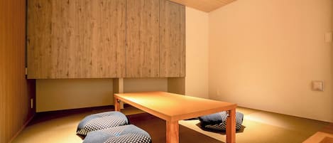 Quarto minimalista com teto de madeira, uma mesinha baixa e almofadas estampadas.