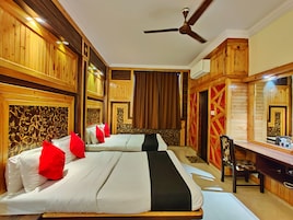 Quarto de hotel com duas camas, uma escrivaninha e um ventilador de teto.