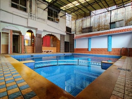 Piscina interior com paredes e chão revestidos em azulejo.