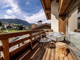 Um deck de madeira com um sofá e uma mesa, com vista para uma paisagem montanhosa.