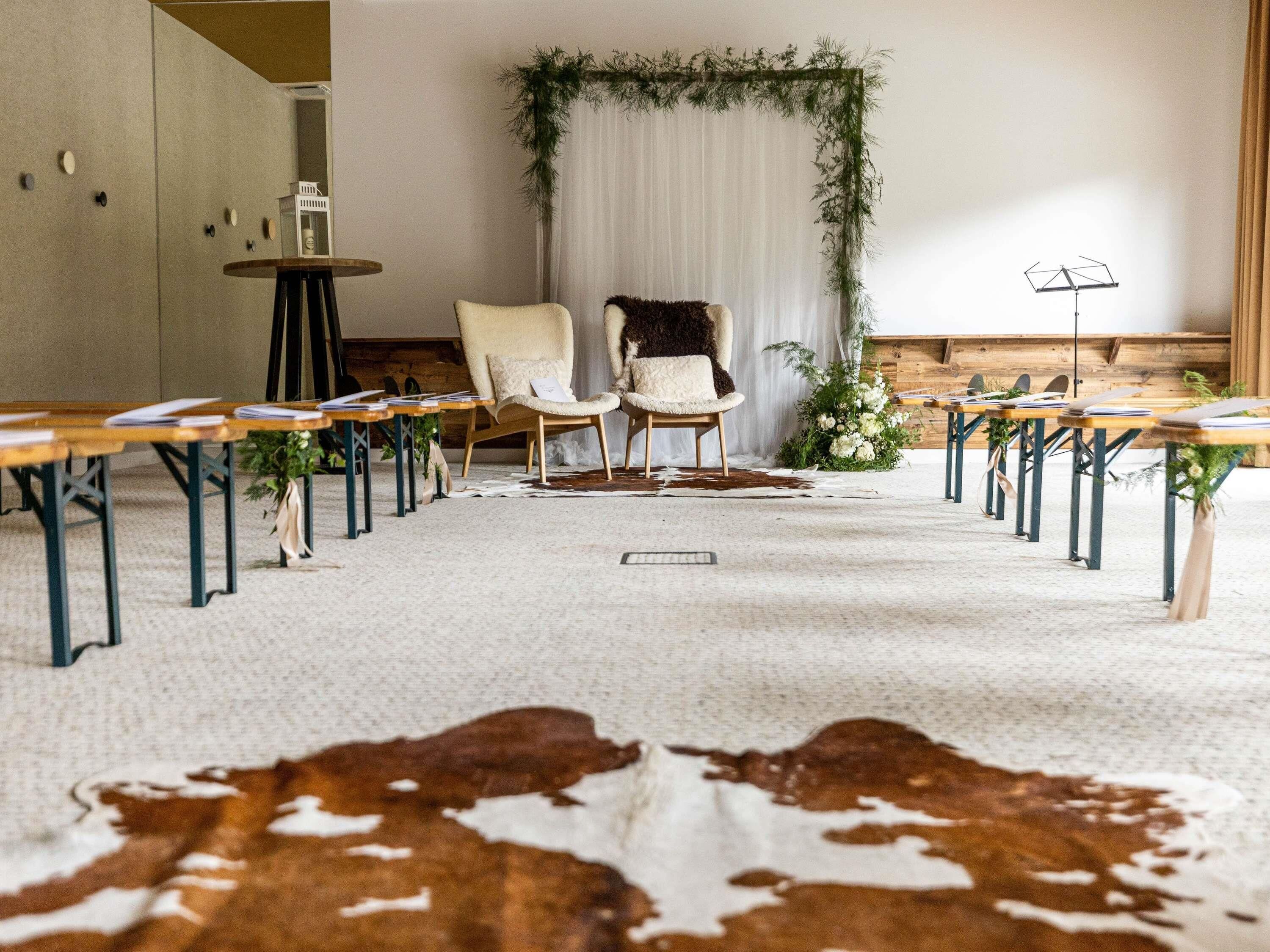 Um quarto com tapete de couro, cortina branca e mesa de madeira com cadeiras.