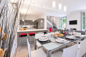 Uma cozinha moderna com área de jantar posta para uma refeição, escada e televisão fixada na parede.