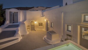 Um edifício de paredes brancas com piscina, uma porta e uma cadeira.