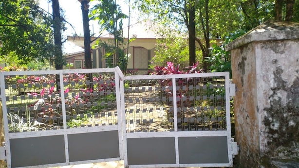 Área cercada com grade de metal e muro de concreto.