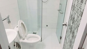 Um banheiro moderno com chuveiro em gabinete de vidro, vaso sanitário branco e pia.