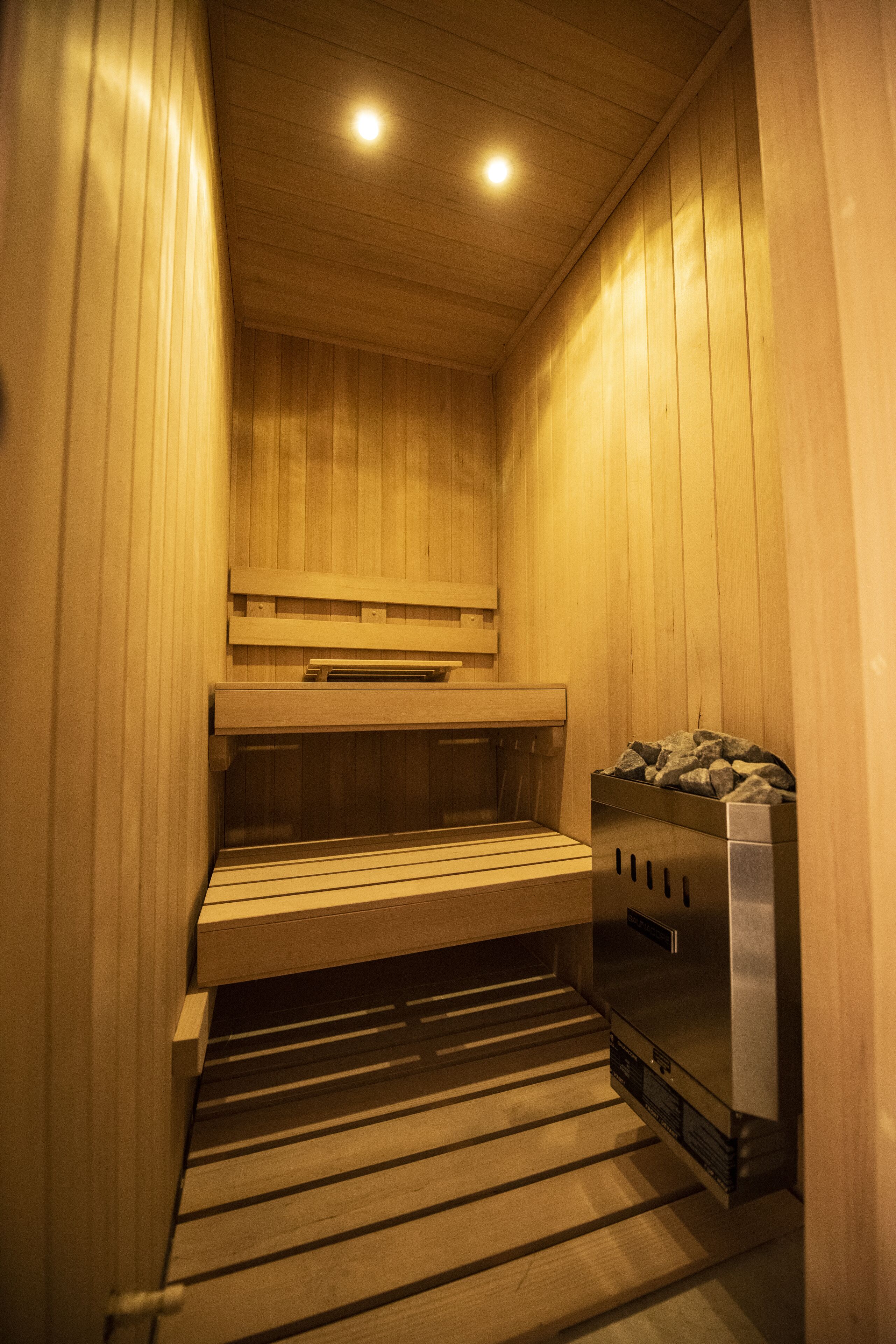 Uma sauna com paredes de madeira, um banco e um gerador de vapor.