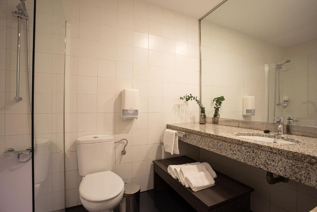 Uma casa de banho moderna com sanita, lavatório e chuveiro.