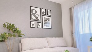 Uma sala de estar moderna com um sofá cinzento, uma mesa de centro e obras de arte emolduradas na parede.