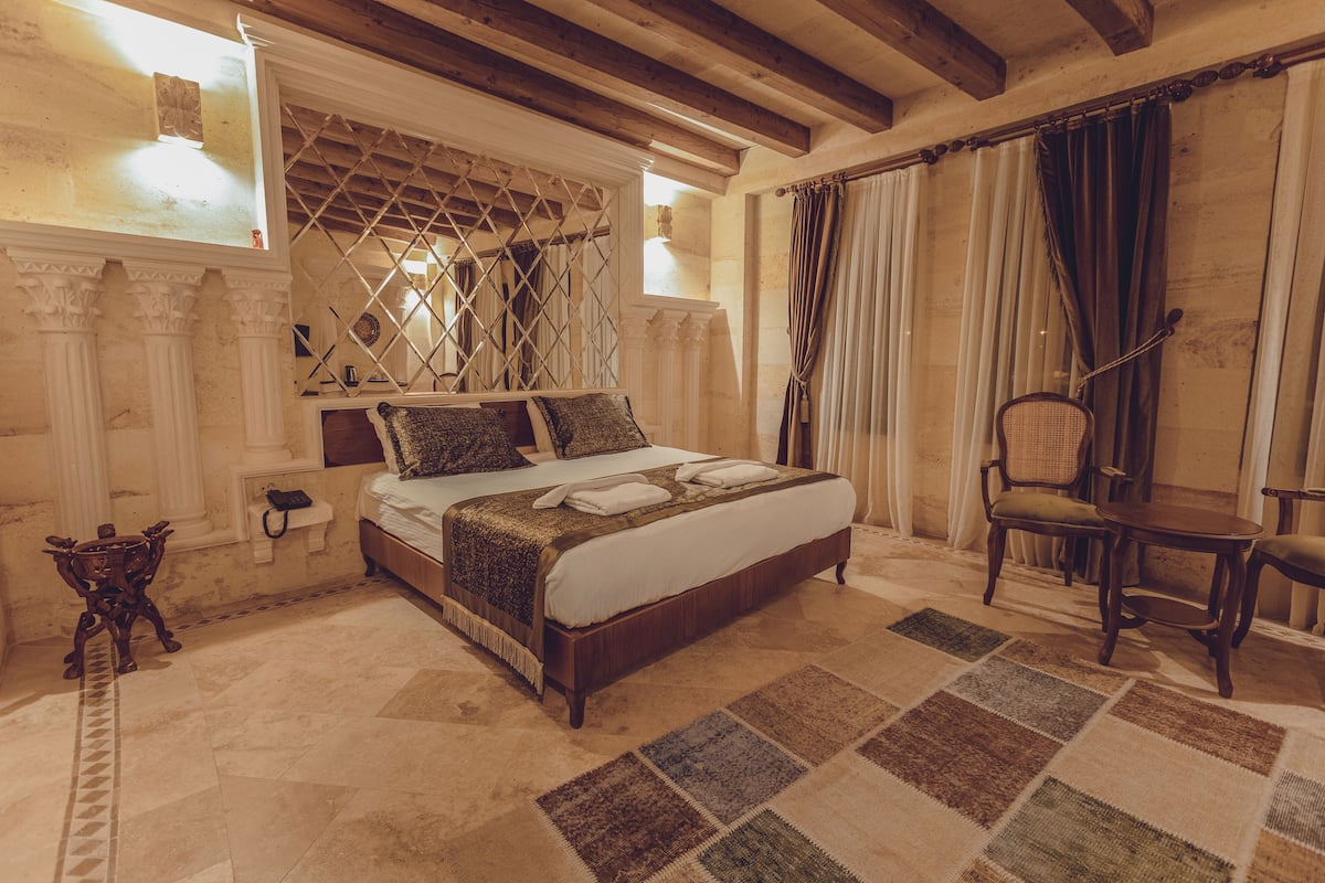 Quarto com uma cama grande, cabeceira de madeira, uma mesa pequena e uma cadeira.