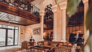 Um hall amplo com tetos altos, um lustre imponente e uma varanda com vista para a região.