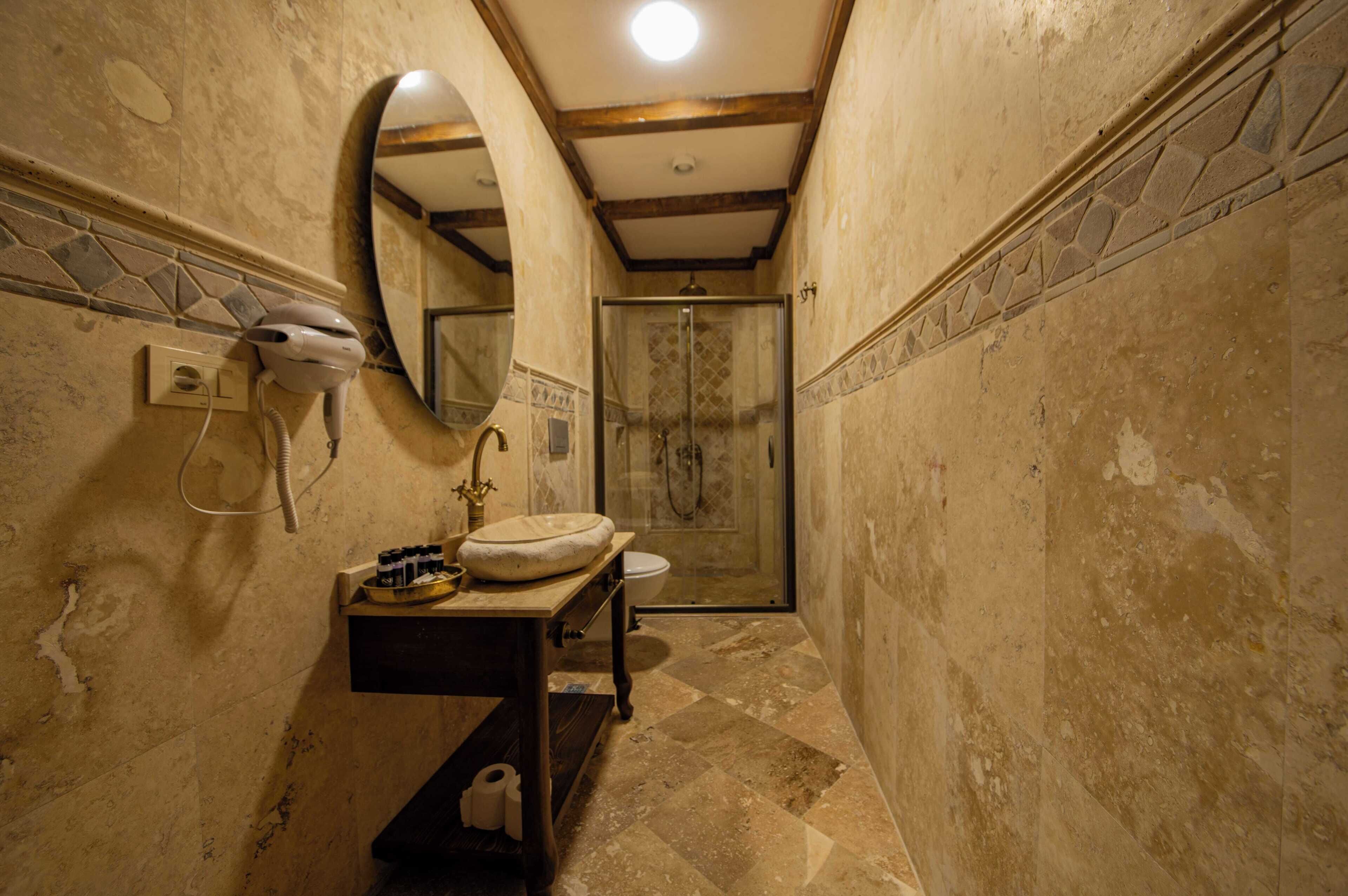 Casa de banho com soalho em mármore, lavatório com espelho em cima e secador de cabelo, além de zona de duche.