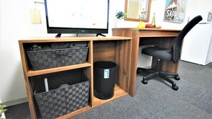Um espaço de trabalho com monitor de computador, cadeira de escritório e estantes.