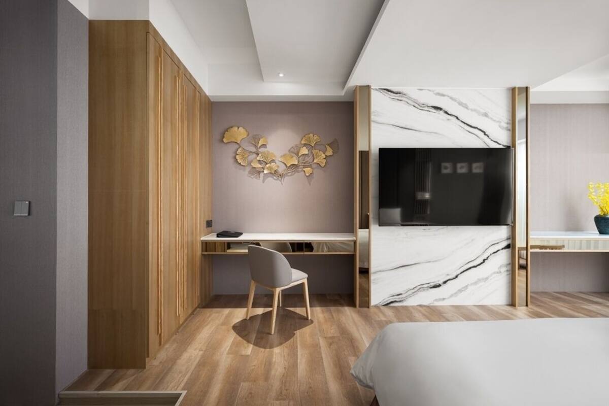 Quarto moderno com guarda-roupa de madeira, uma escrivaninha com cadeira, uma cama e uma parede decorada com mármore.