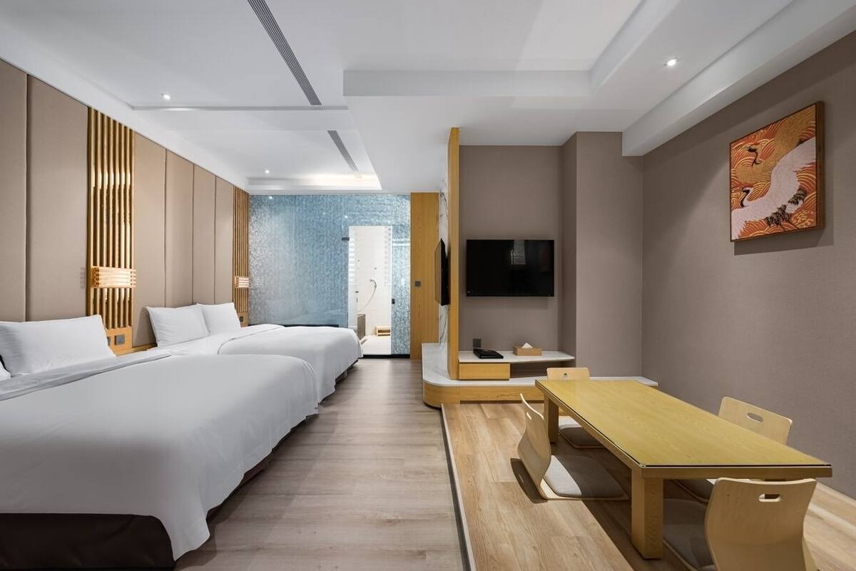 Quarto de hotel com cama, escrivaninha e televisão.