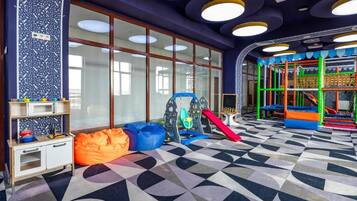 Uma área de recreação infantil com piso estampado em padrões geométricos, um escorregador e uma estrutura de escalada.