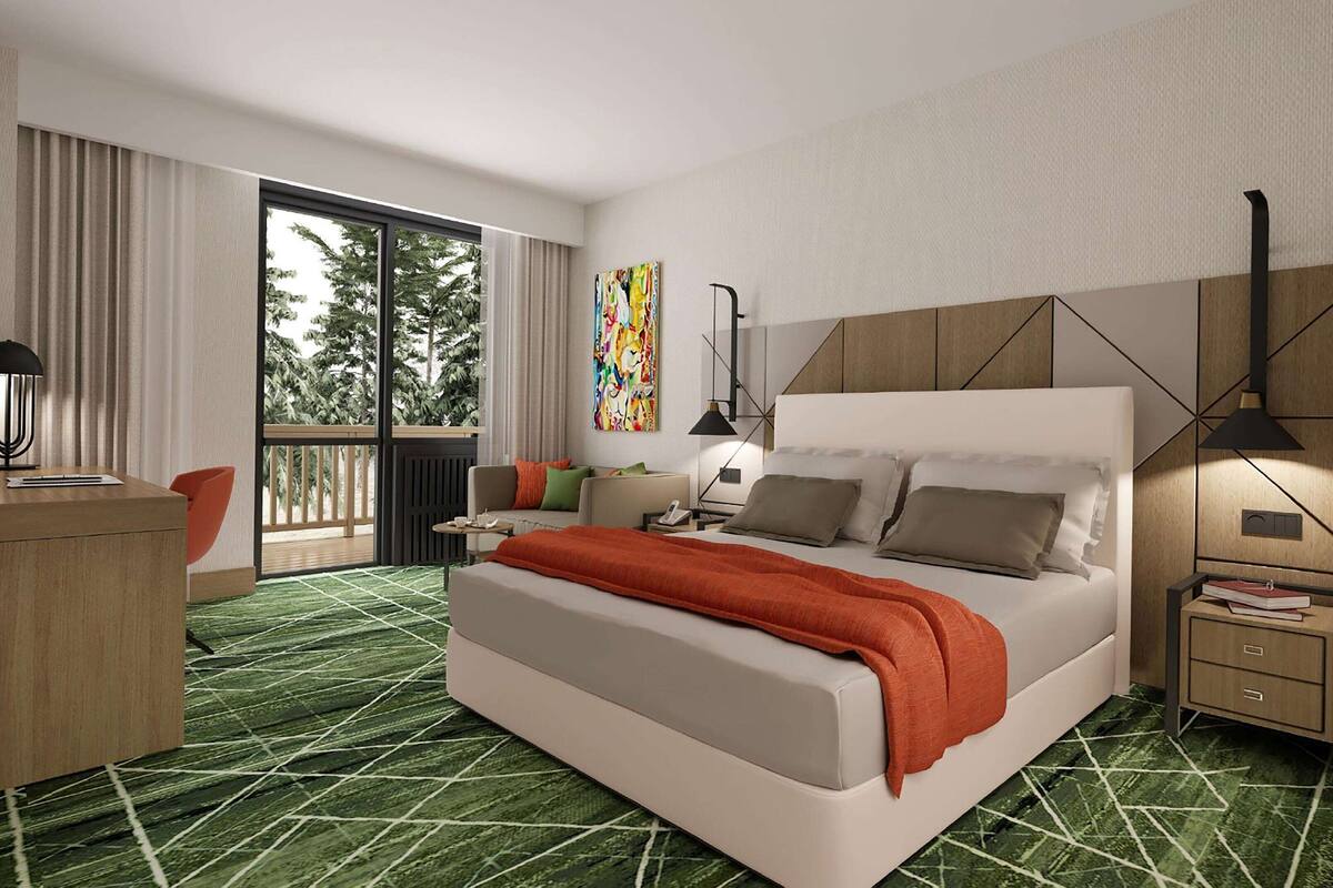 Quarto de hotel moderno com uma cama grande, uma escrivaninha, uma cadeira, uma mesinha de cabeceira e um quadro na parede.