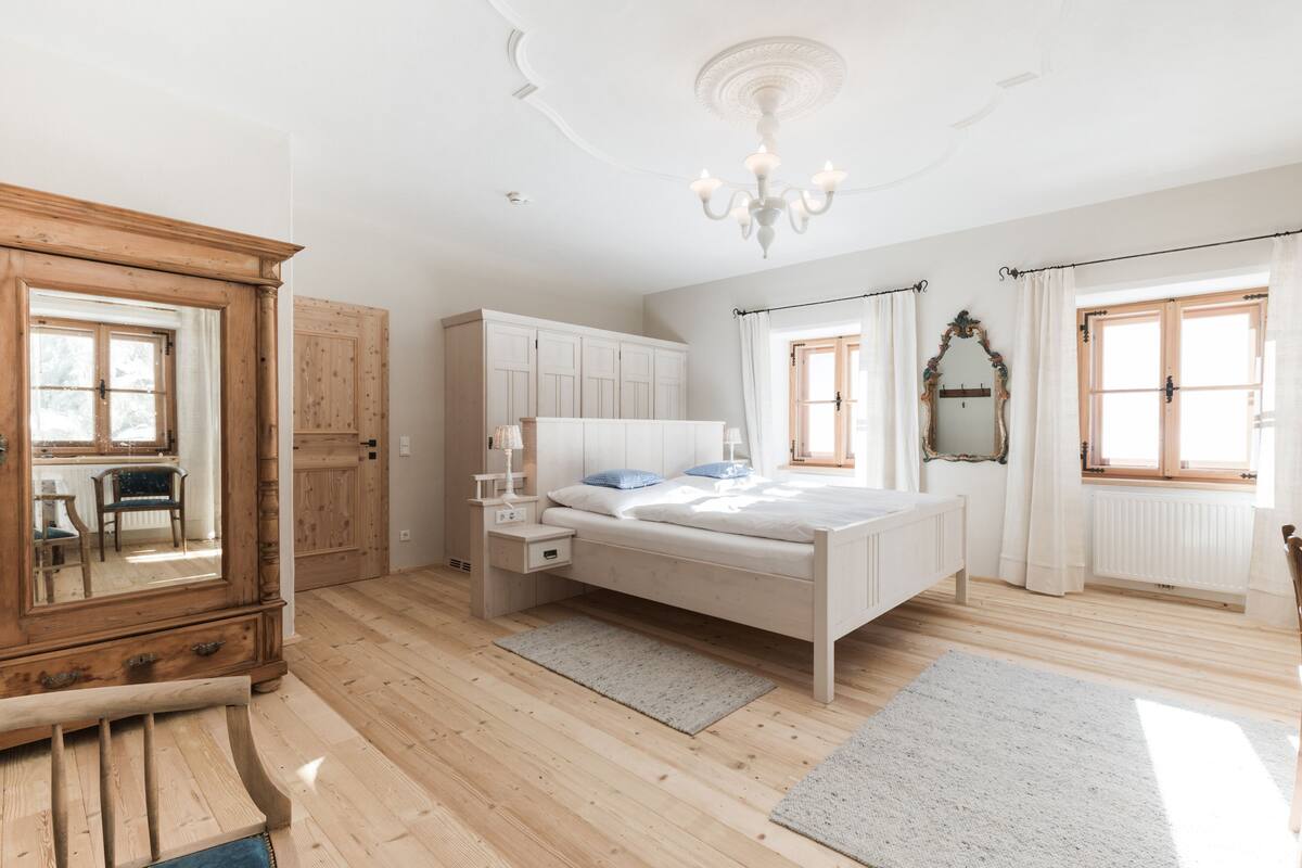 Quarto com cama, guarda-roupa de madeira e espelho.