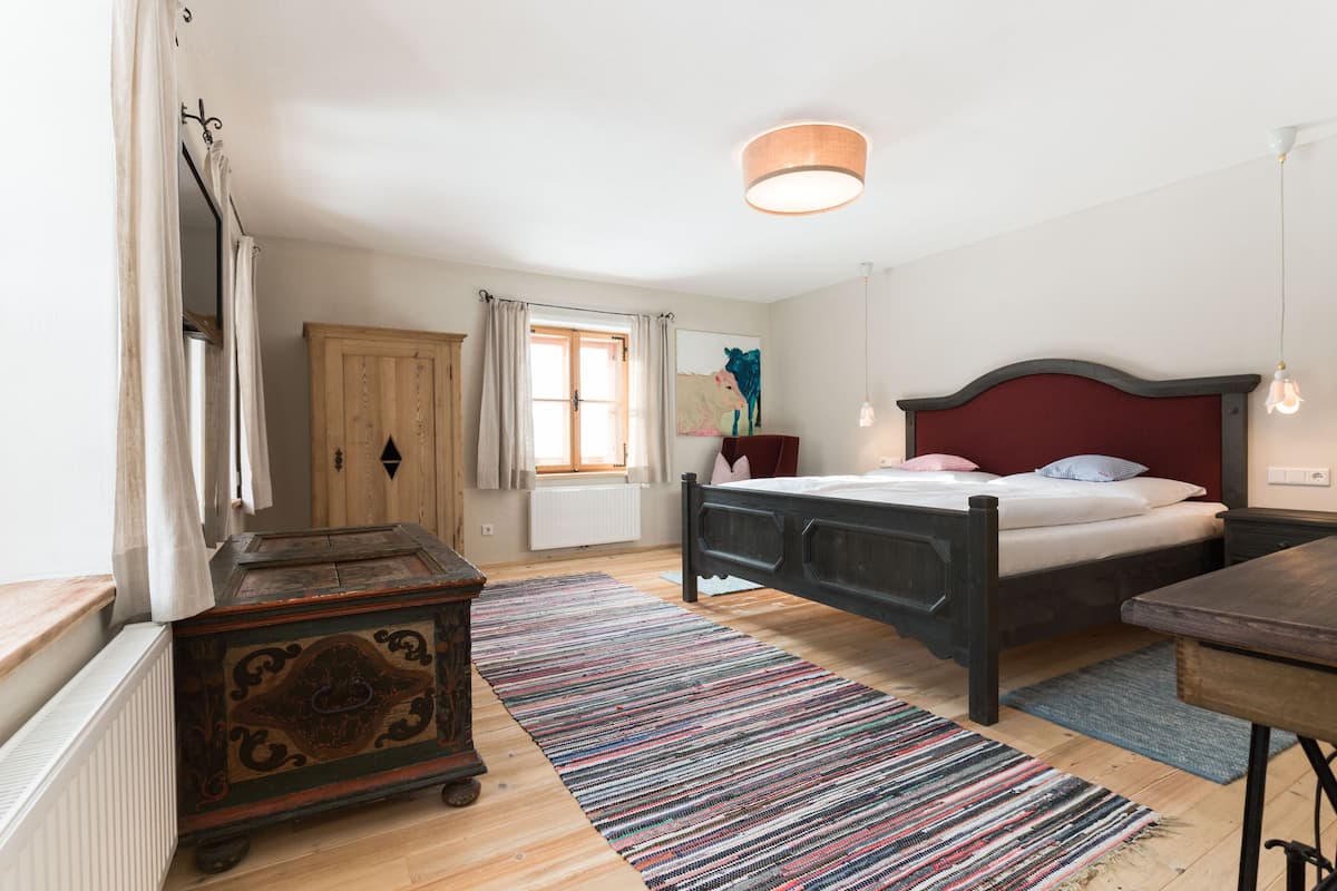 Quarto com cama, cómoda de madeira e janela com cortinas.