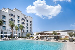 Um hotel com área de piscina, espreguiçadeiras e guarda-sóis.